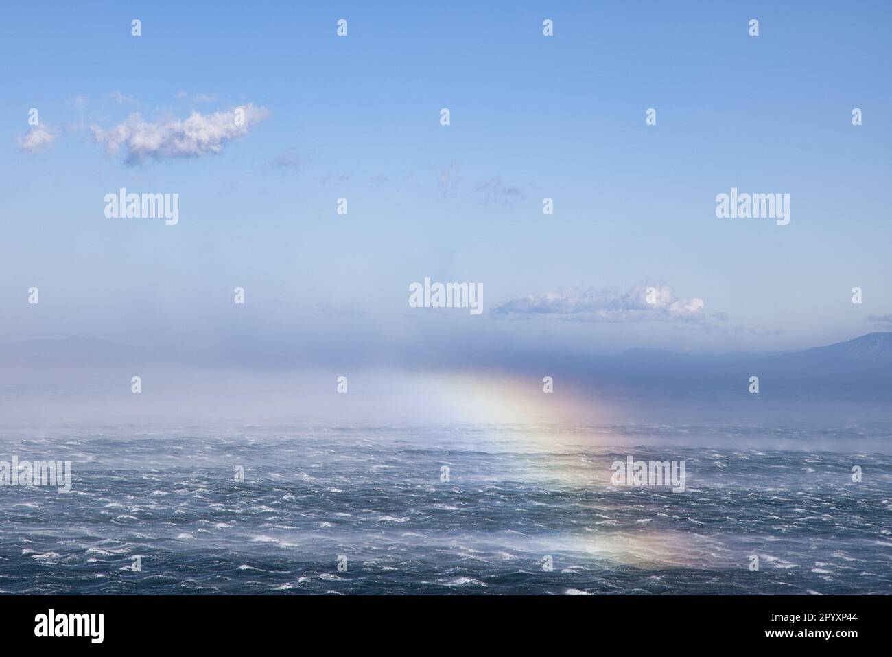 A magnificent rainbow arcs across a stunning blue sky above a vast ...
