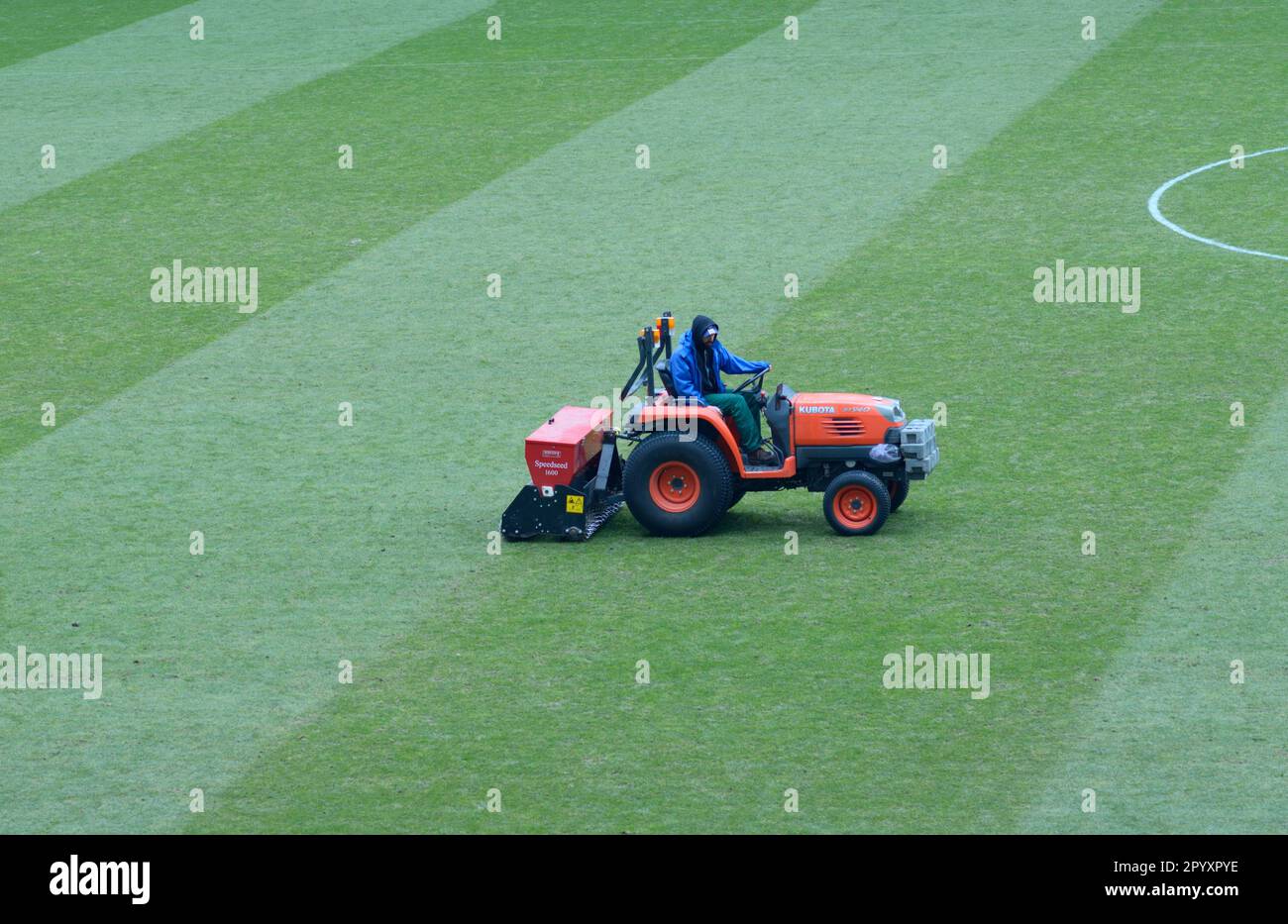 Worker driving tractor cleaning lawn on a football field of the stadium ...