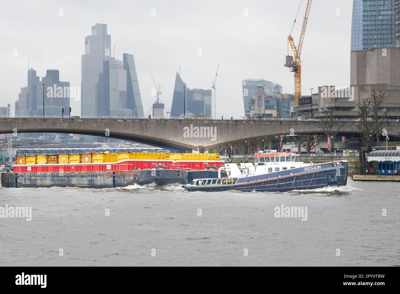 The tug Regain pulls a couple of barges with refuse containers under ...