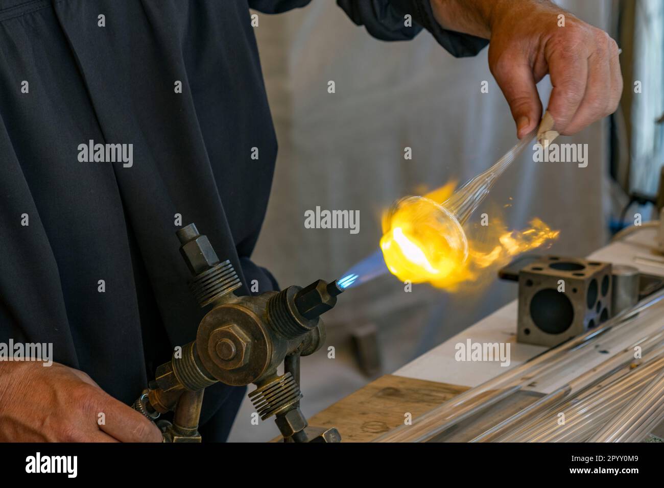 glass blower who shapes glass heated by the flame of the burner Stock ...