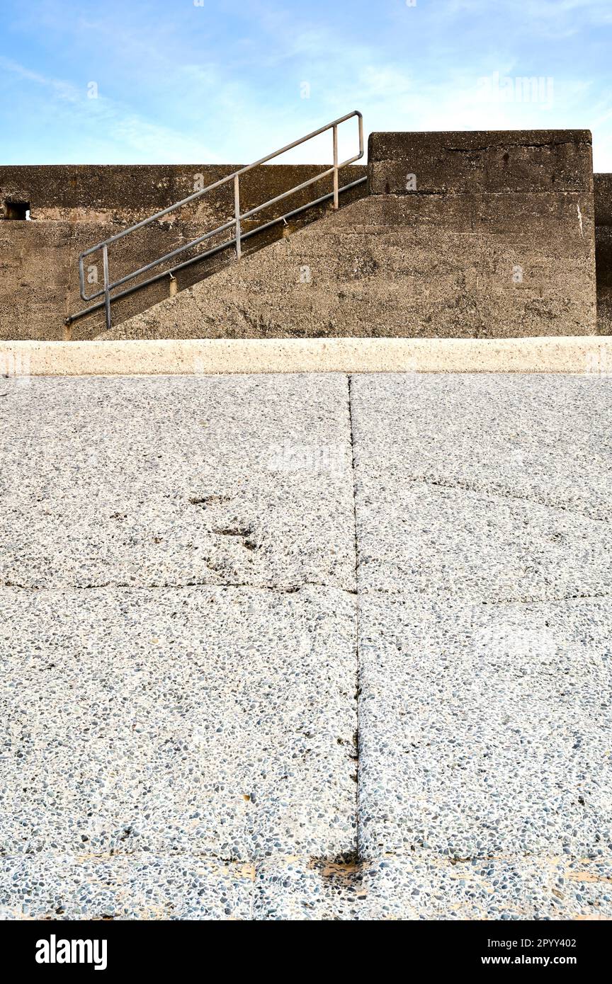 Concrete slope with rails going down to seawall Stock Photo - Alamy