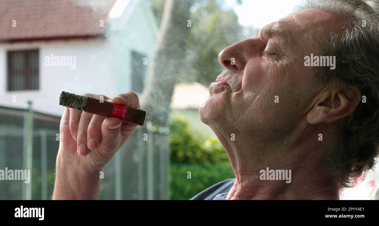 Older man enjoying retirement smoking a cigar outside Stock Photo - Alamy