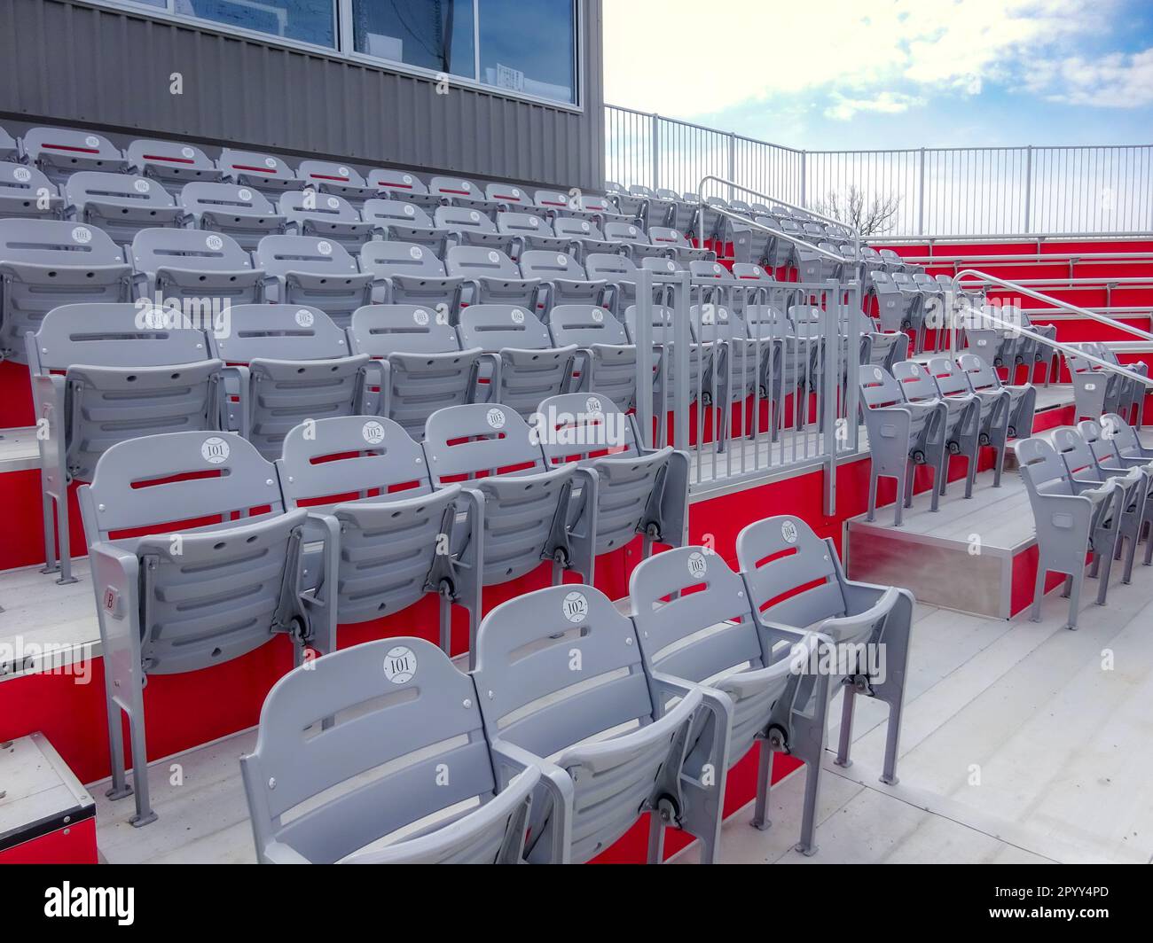 Rows of empty gray seats in a stadium with silver number tags shaped ...