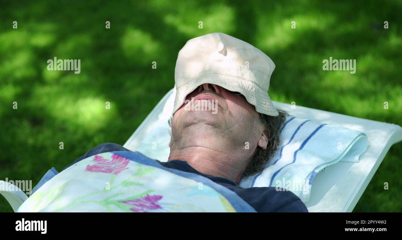 Older man napping outside covered by hat. Retired senior person ...