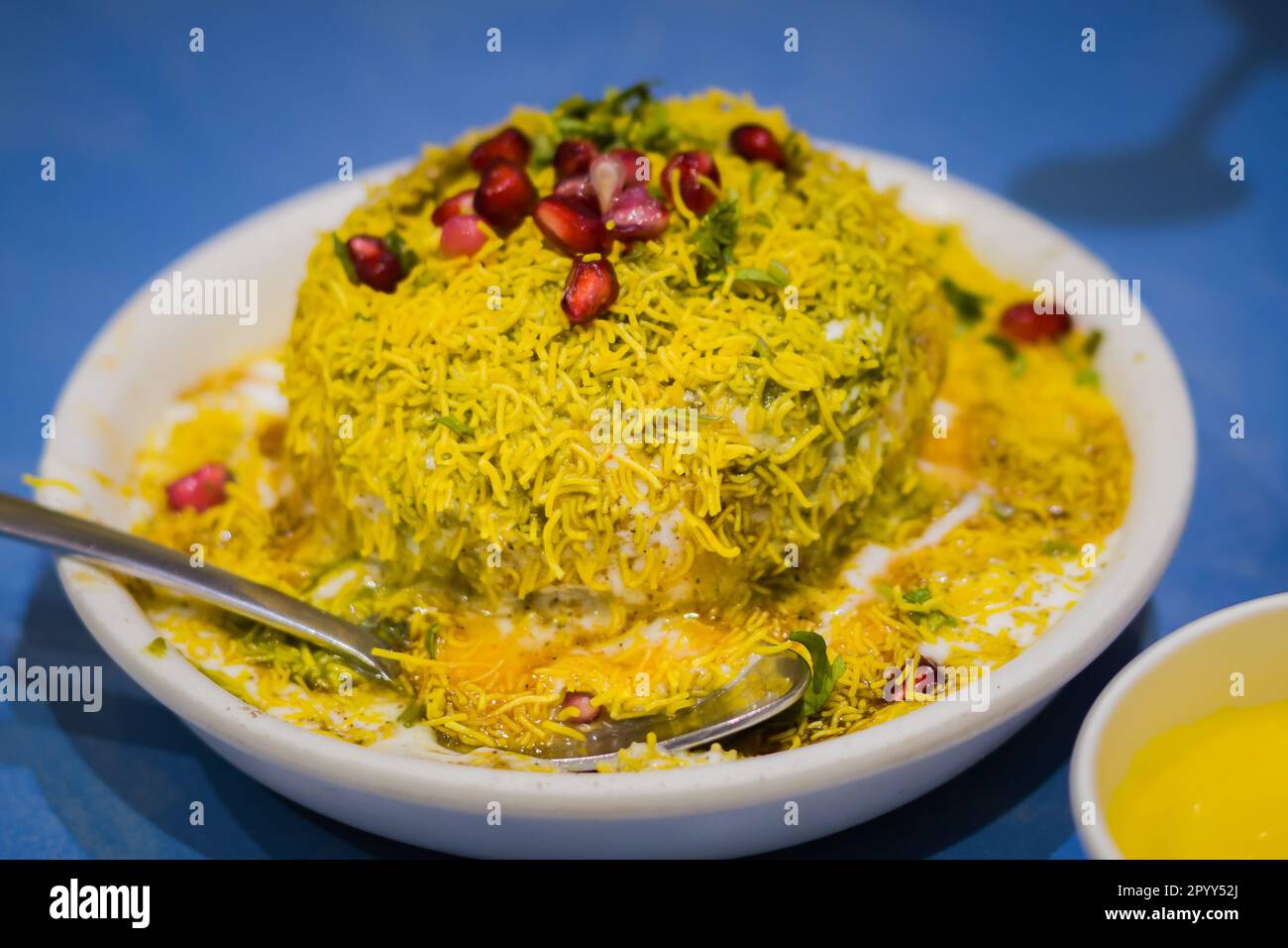 Dahi vada chaat served on a plate garnished with Sev and pomegranate ...