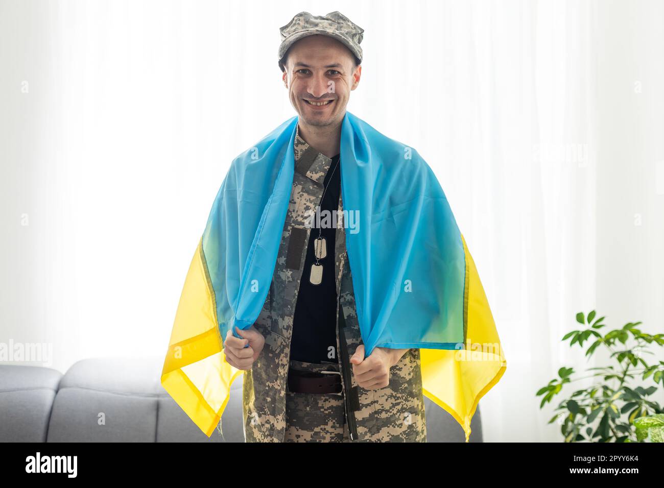 Portrait of a courageous Ukrainian military man holding the flag of ...