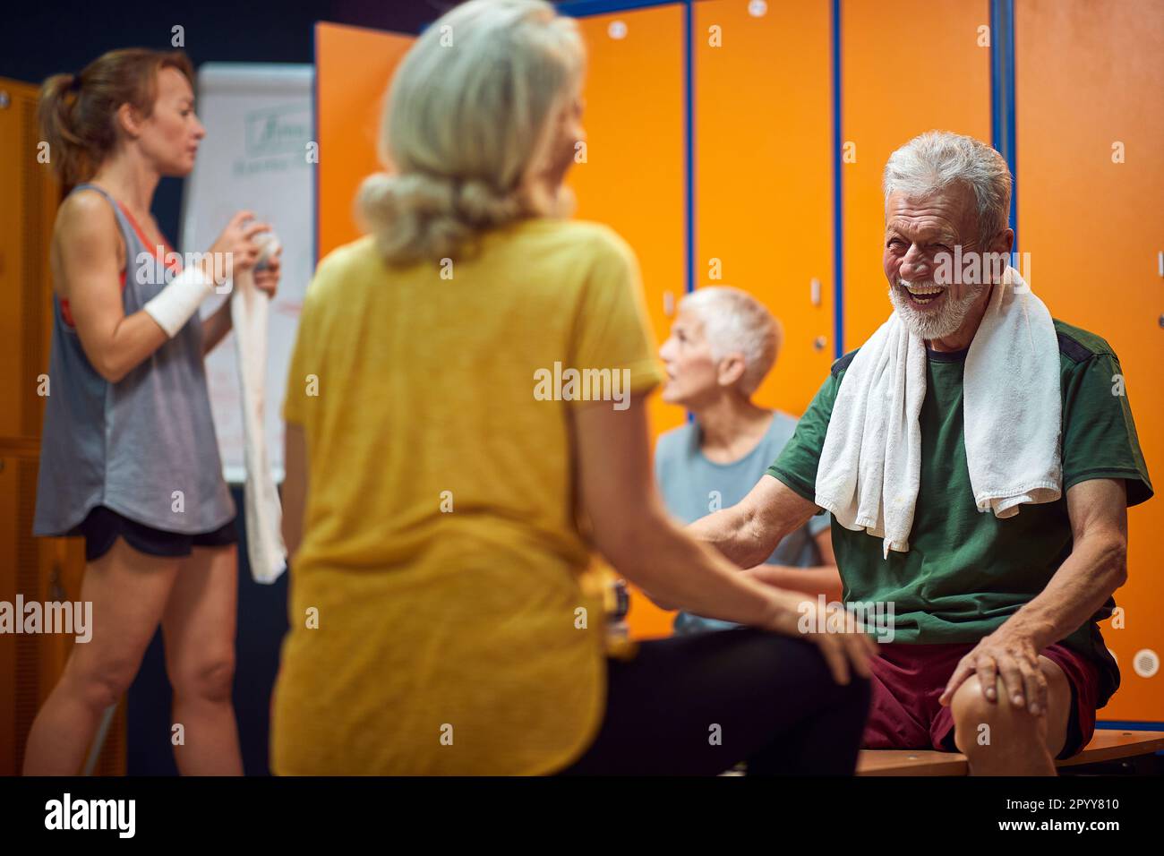 Group of people in gym locker room, senior man and woman talking and ...