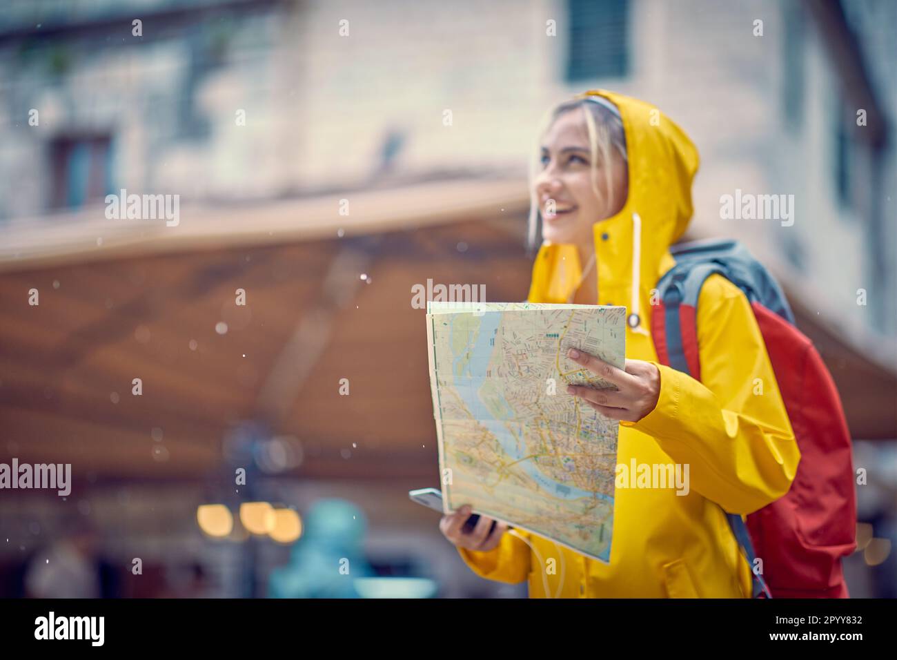 Joyful Woman With Map In Rain Looking Happy Walk Through The City In Raincoat Summertime Rain