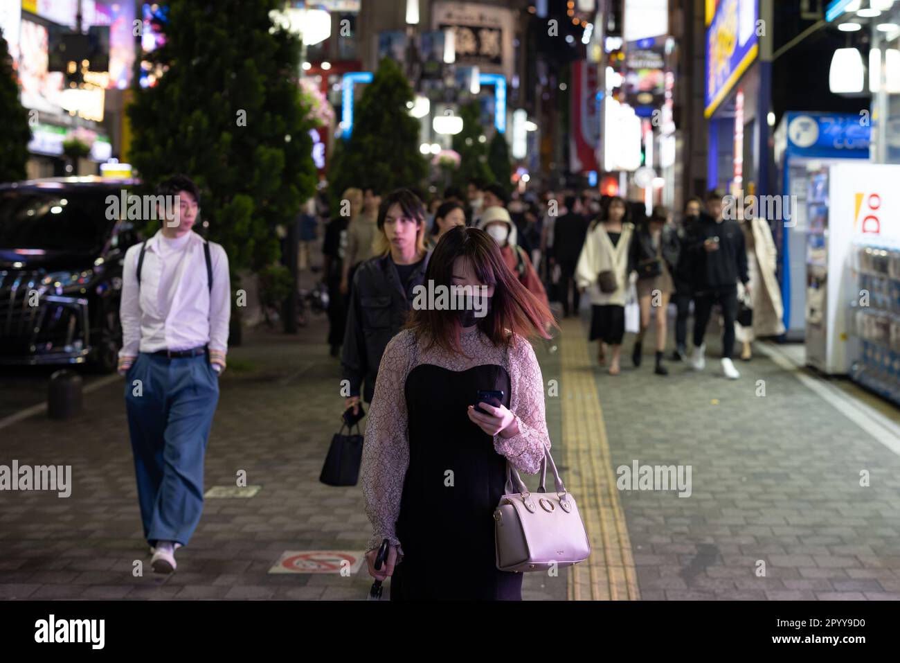 Japanese woman with a face mask walks in the streets of Kabukicho ...