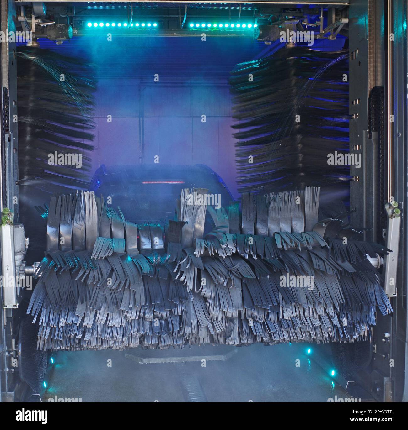 The rotating brushes of a car wash in action. In the blue haze you can ...