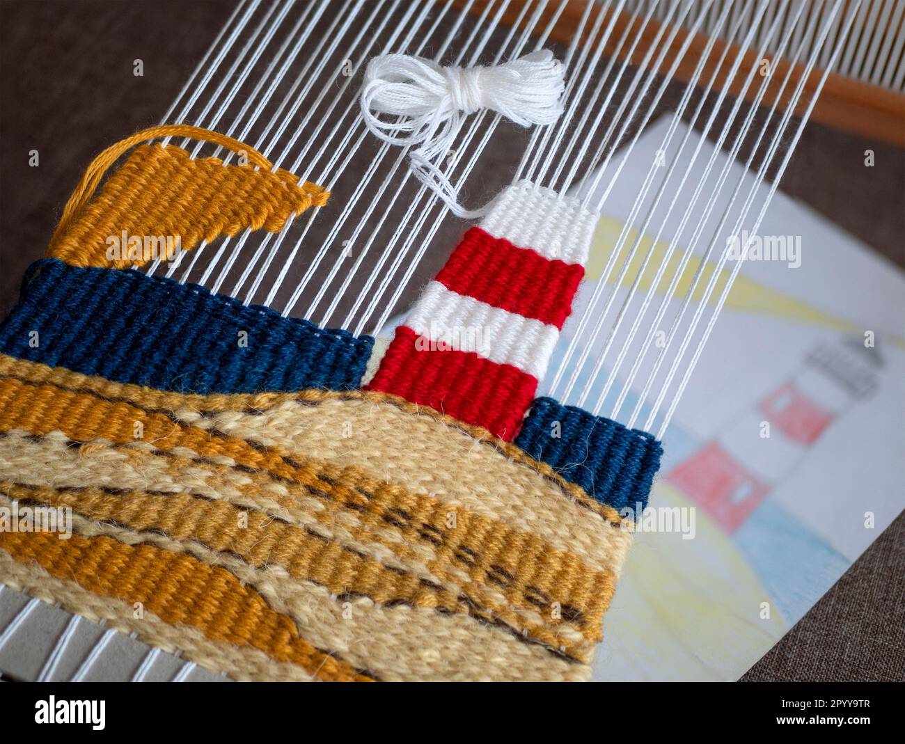 Making a tapestry with a picture of a lighthouse following the sketch ...