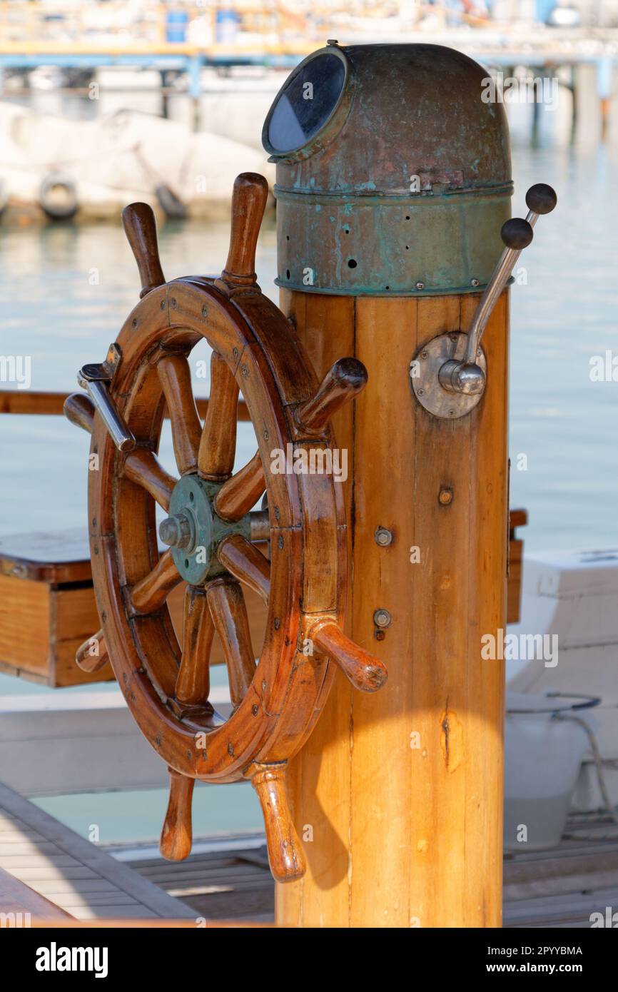 A wooden boat wheel with a wooden handle, mounted on a dock in an ...
