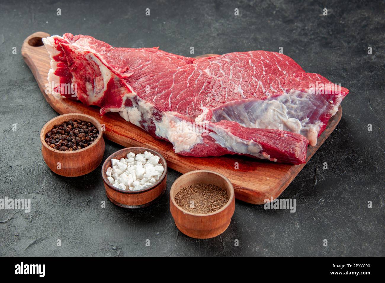front view raw meat slice with salt and pepper on dark background ...