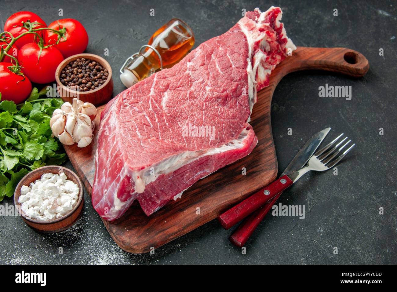 front view raw meat slice with tomatoes seasonings and greens on dark ...