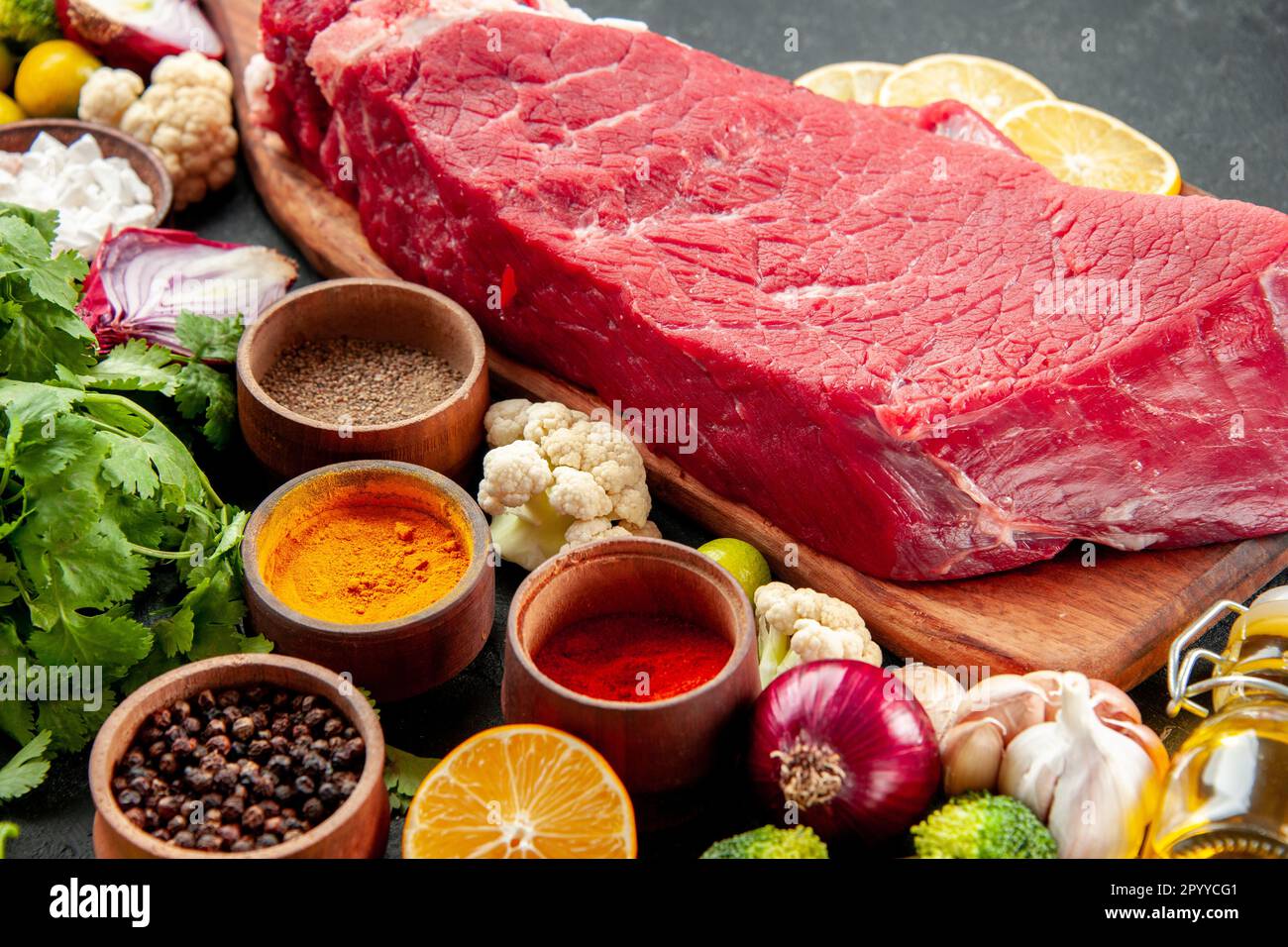 front view raw meat slice with vegetables greens and seasonings on dark ...