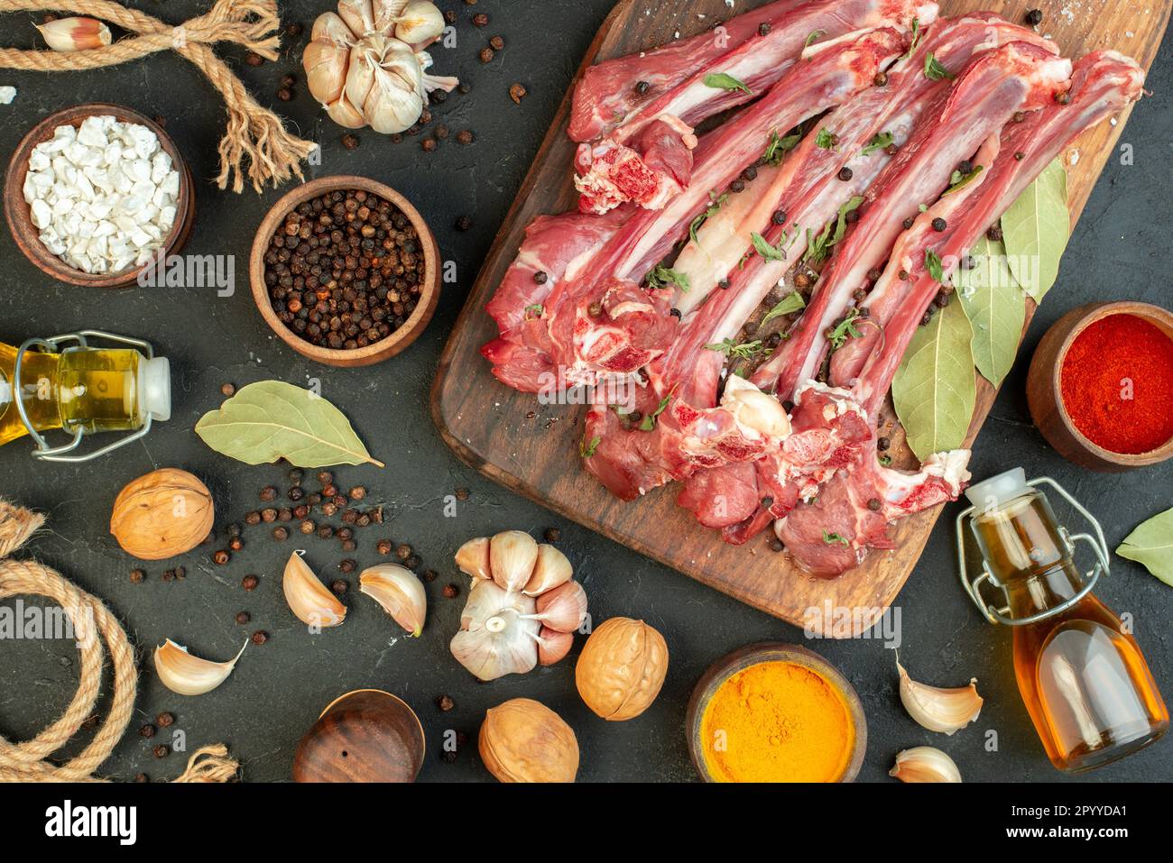 top view raw meat slice with different seasonings on a dark background ...