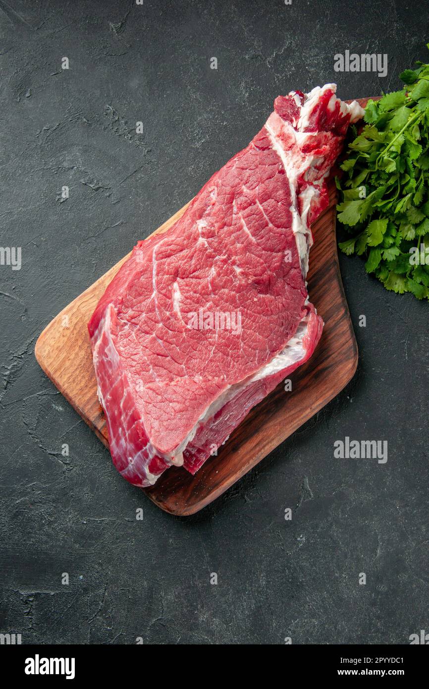 top view raw meat slice with greens on a dark background color food ...