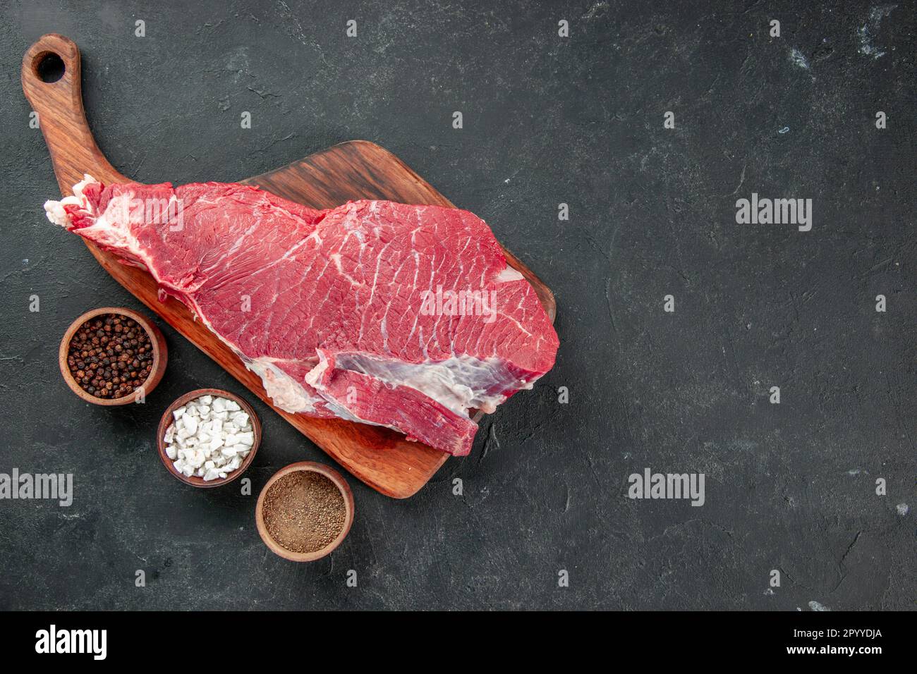 top view raw meat slice with salt and pepper on dark background cooking ...