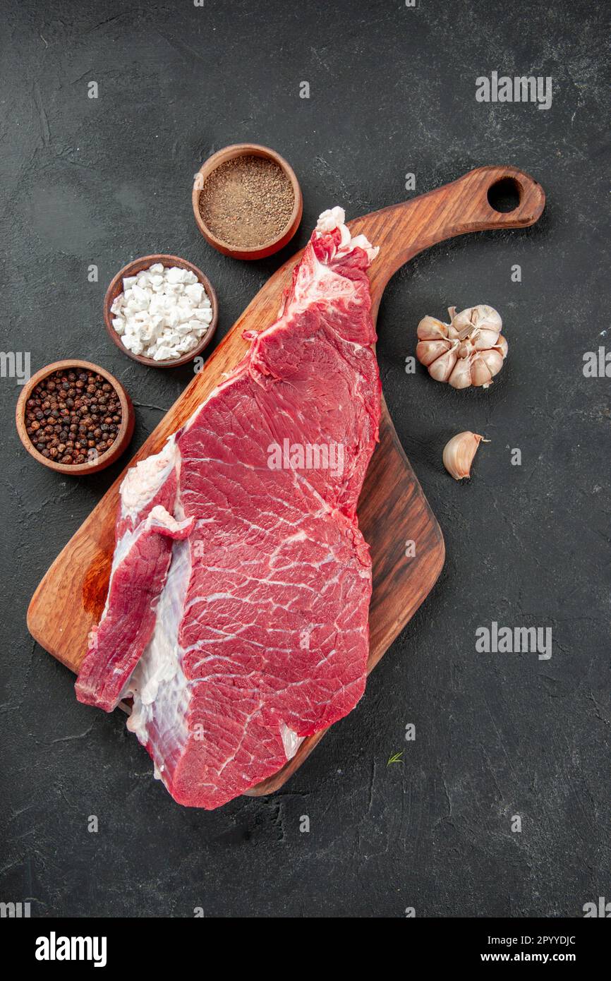 top view raw meat slice with salt and pepper on a dark background ...