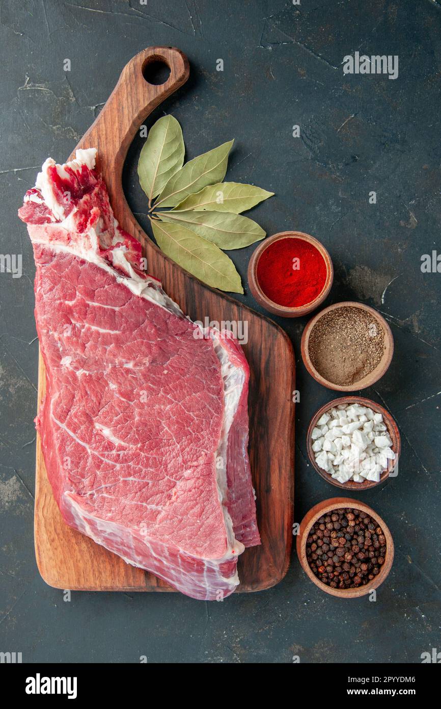 top view raw meat slice with seasonings on dark background color ...