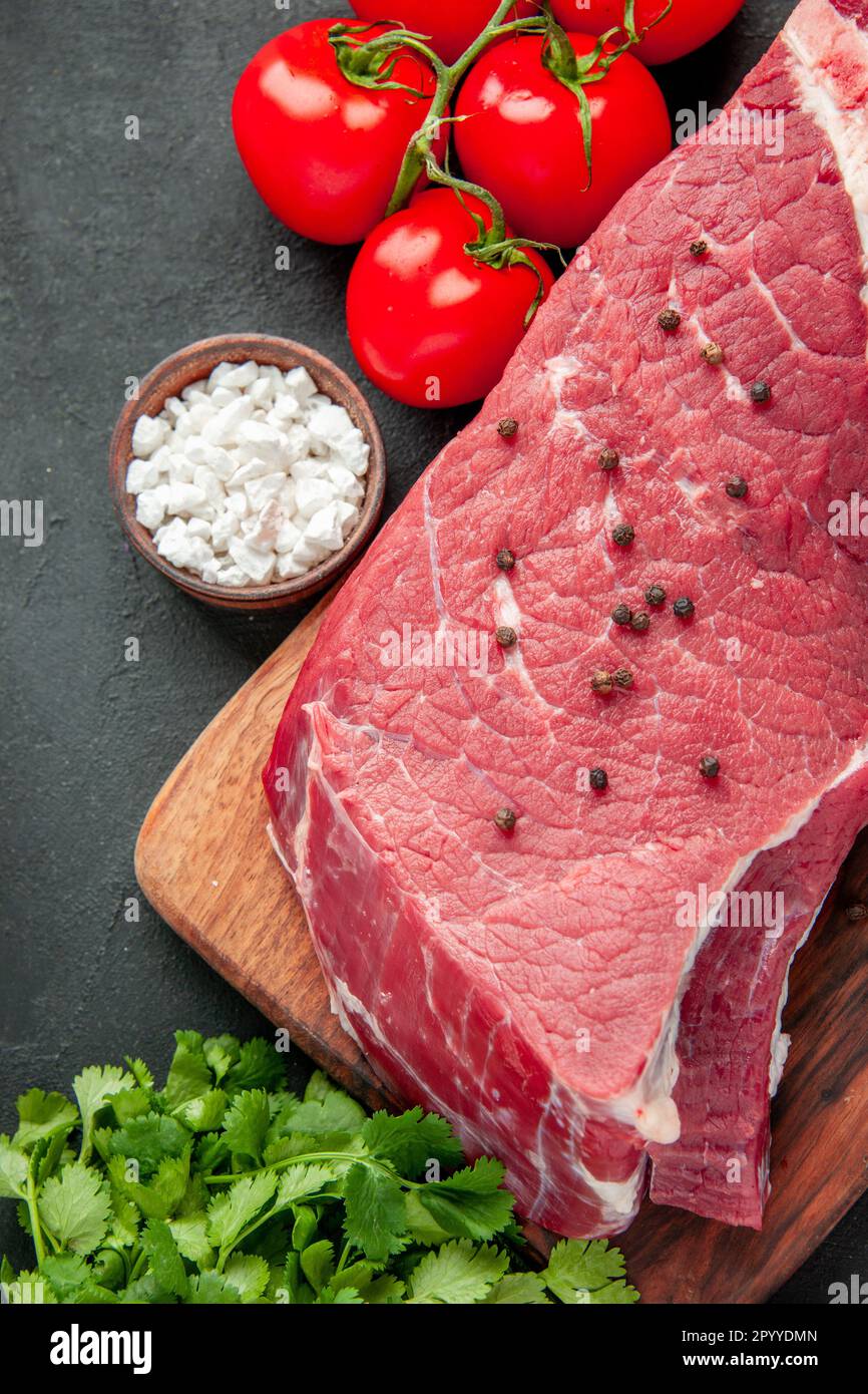 top view raw meat slice with seasonings and tomatoes on dark background ...