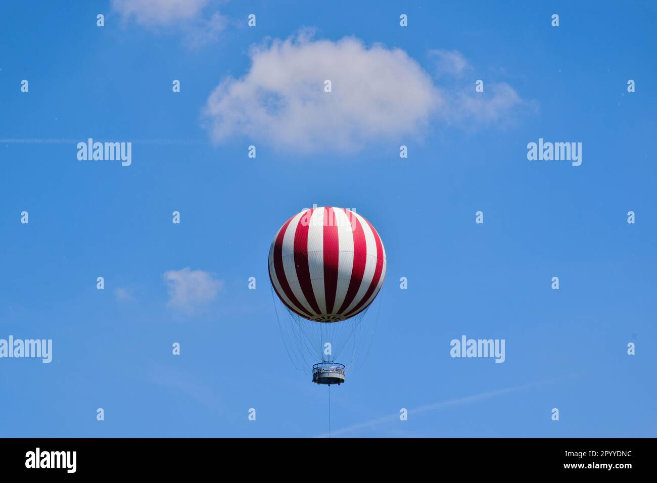 isolated red and white adventure balloon up high. suspended basket and ...