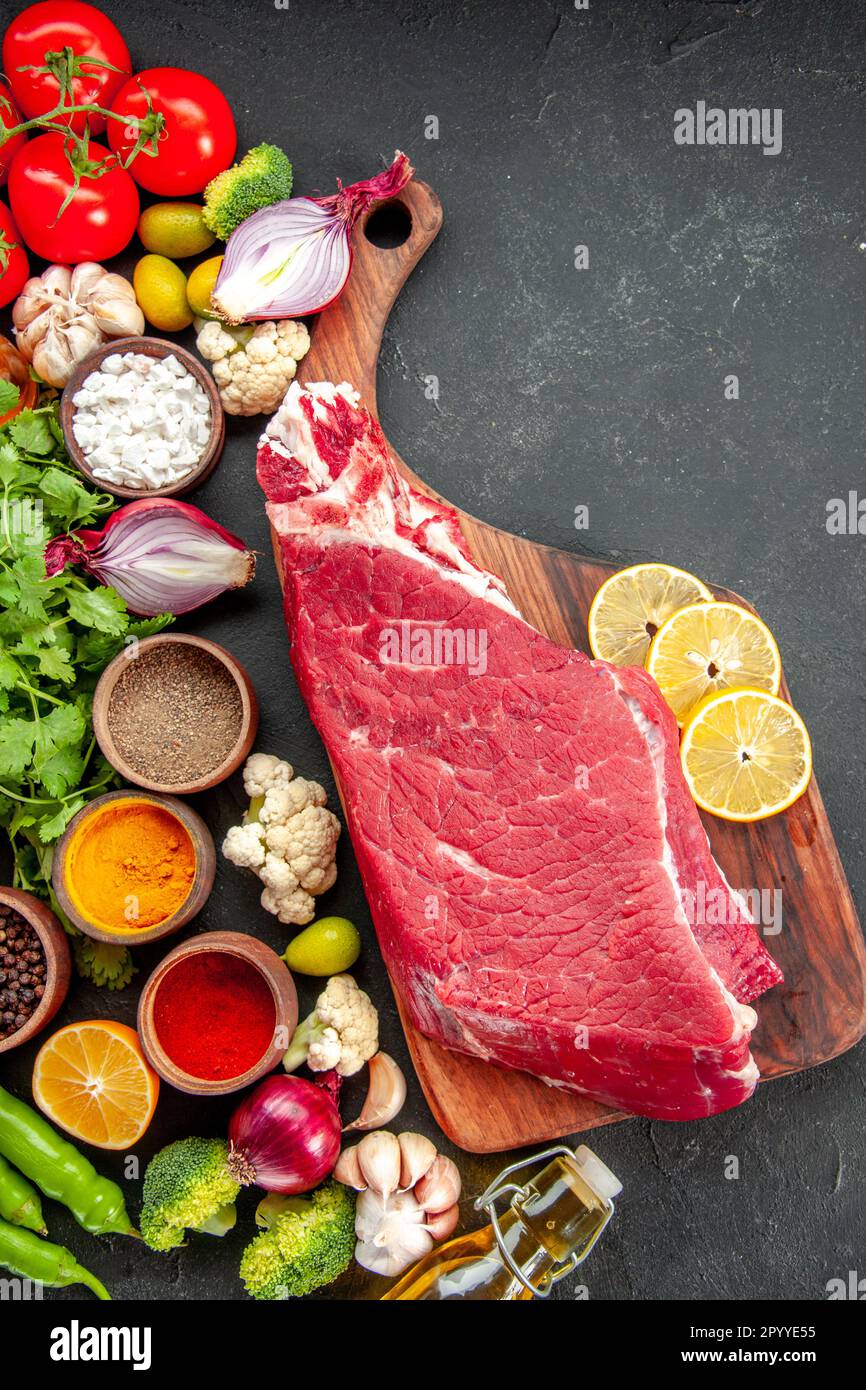 top view raw meat slice with vegetables greens and seasonings on the ...