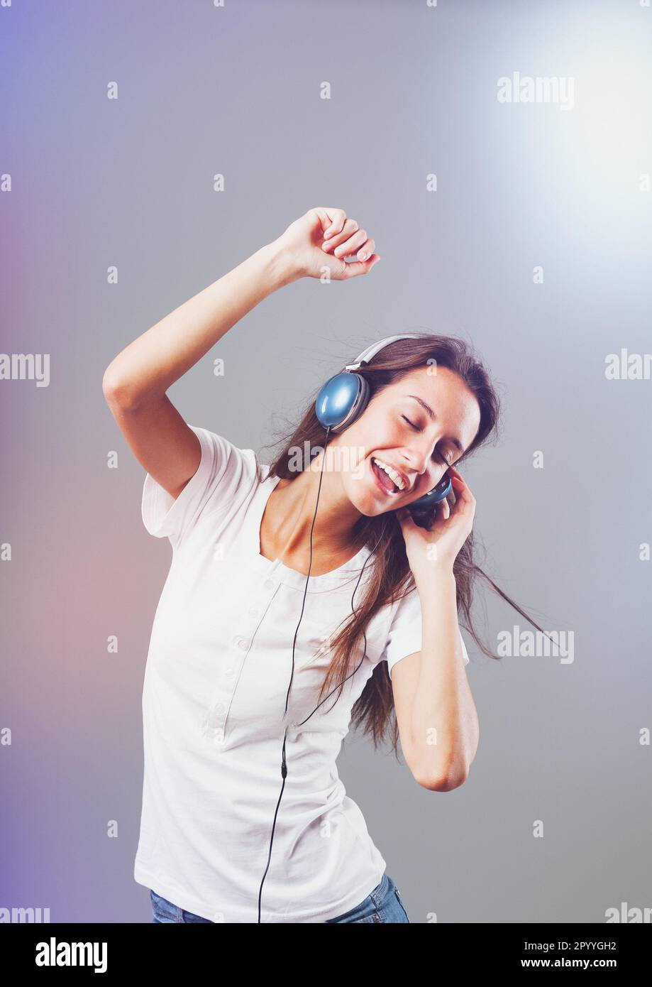 Girl wearing blue headphones listens to music, dancing and singing ...