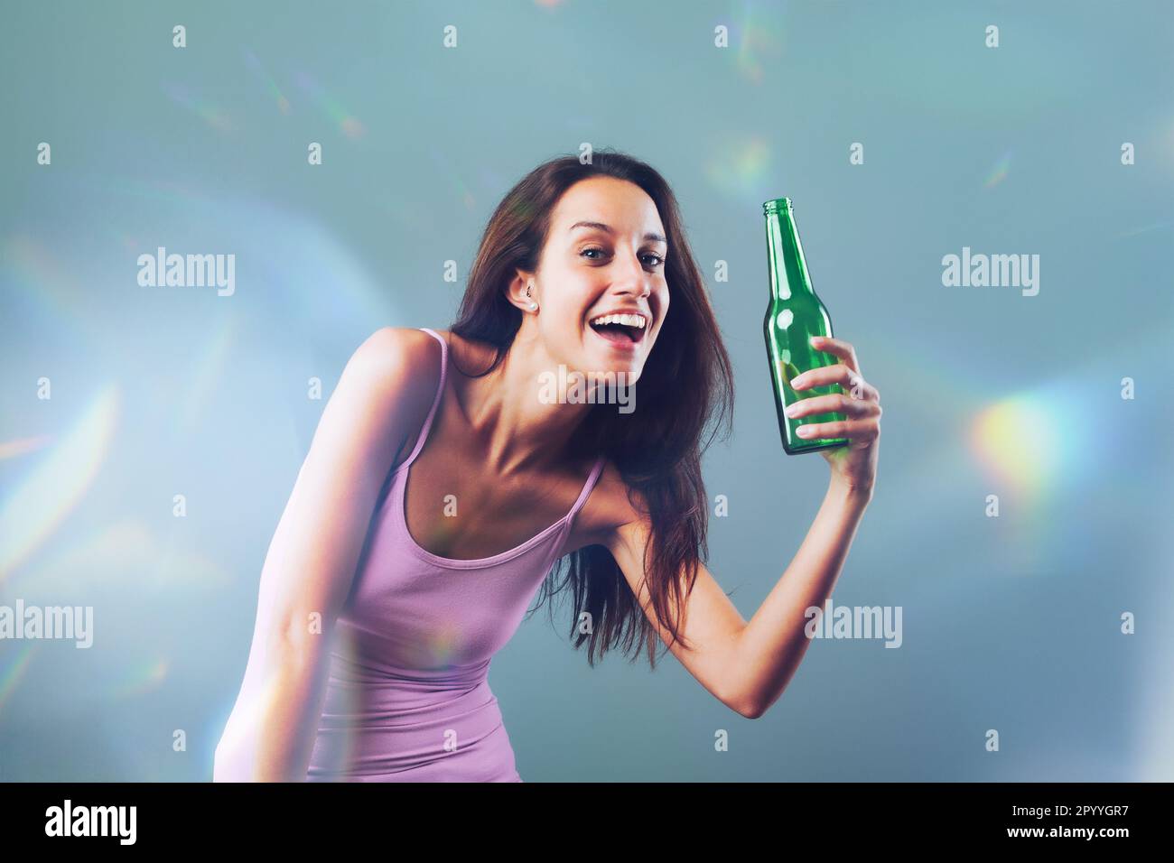 Girl with green bottle celebrates, appears slightly tipsy. Young woman ...