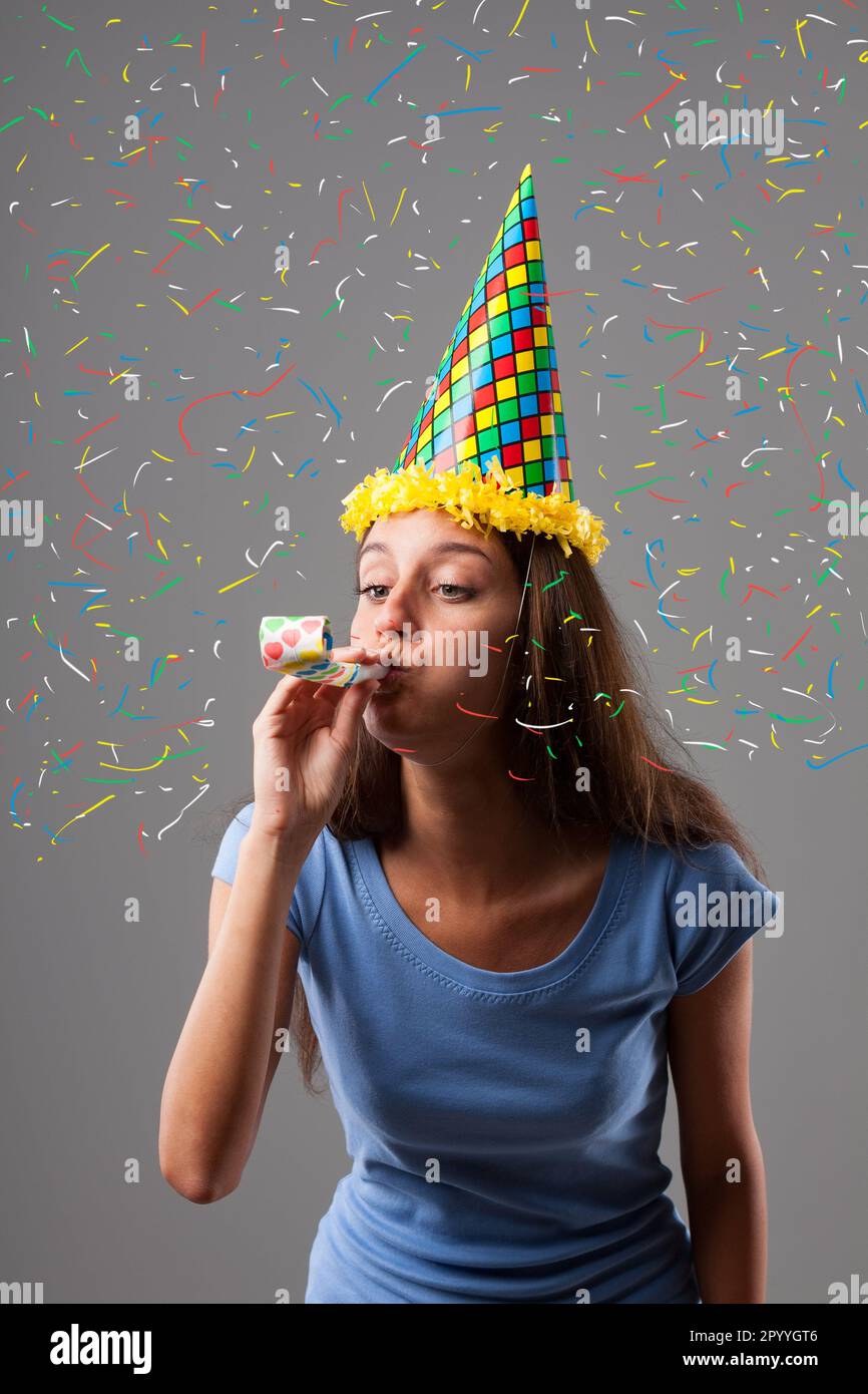 Party girl dons pointed hat, harlequin colors, and horn amidst colorful ...