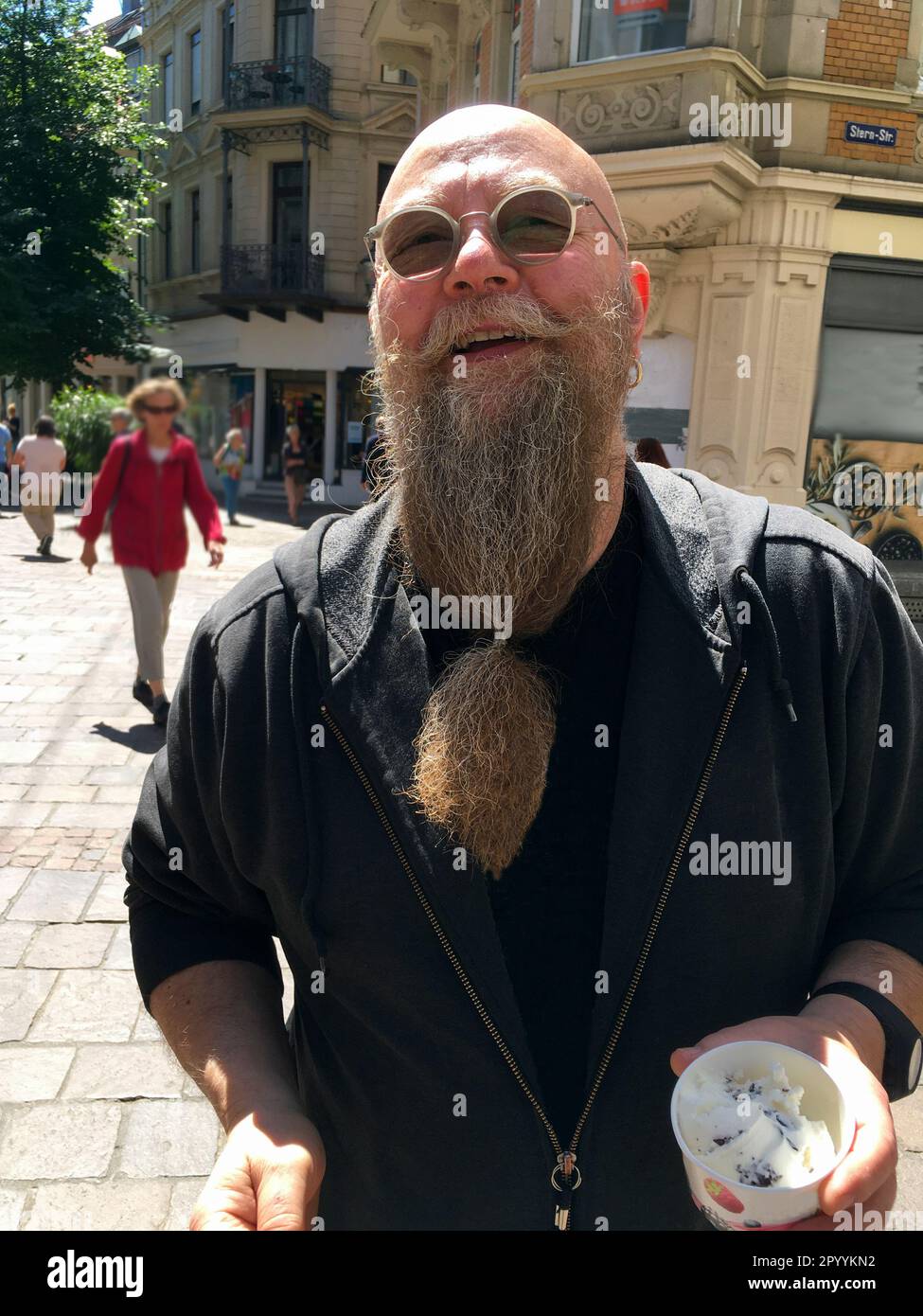 Mann mit langem Bart und Sonnenbrille genießt ein italienisches Eis ...