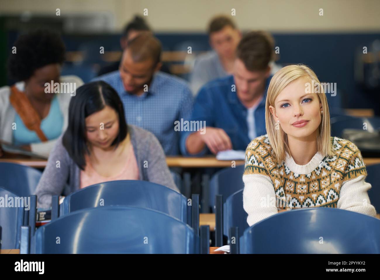 The last exam before the real world begins. A group of students sitting ...