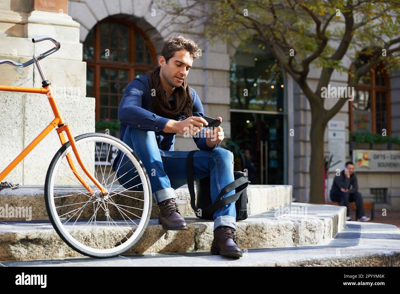 City pit stop. A young man taking a break from riding his bicycle to ...