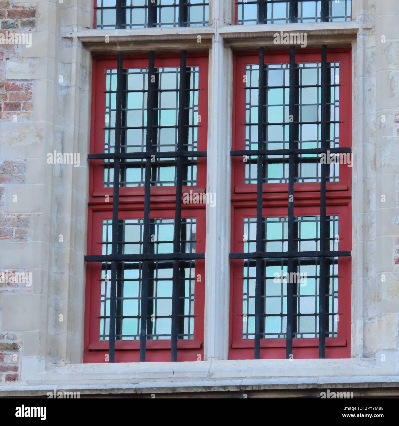 A window with a black metal railing and a bright red frame, overlooking ...