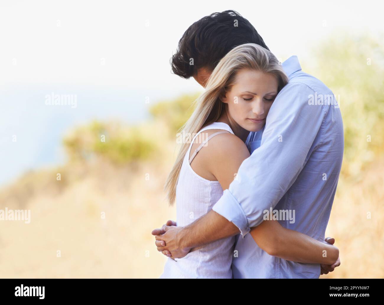 Secure in his arms. Side view of loving young couple embracing ...