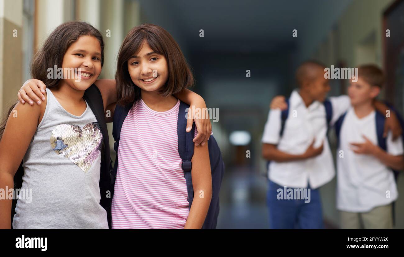 Back to school. Two school girls standing with their arms around each ...
