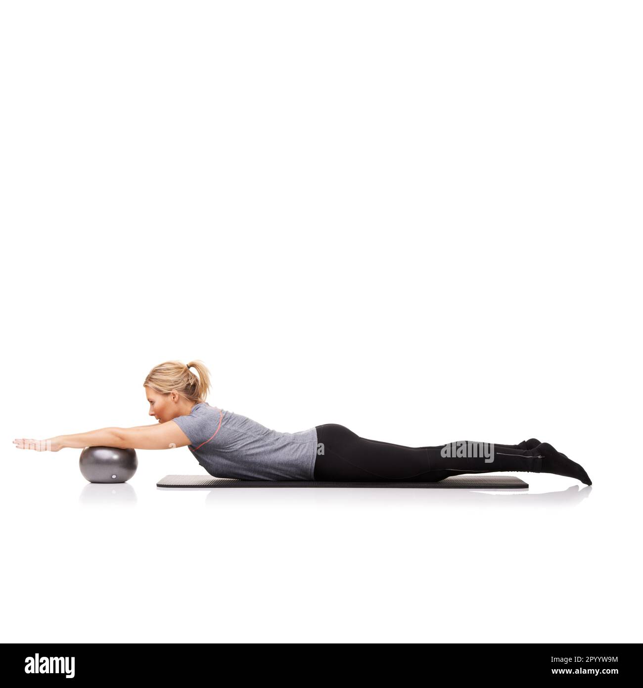 Stretched out on her exercise mat. A young woman using an exercise ball ...