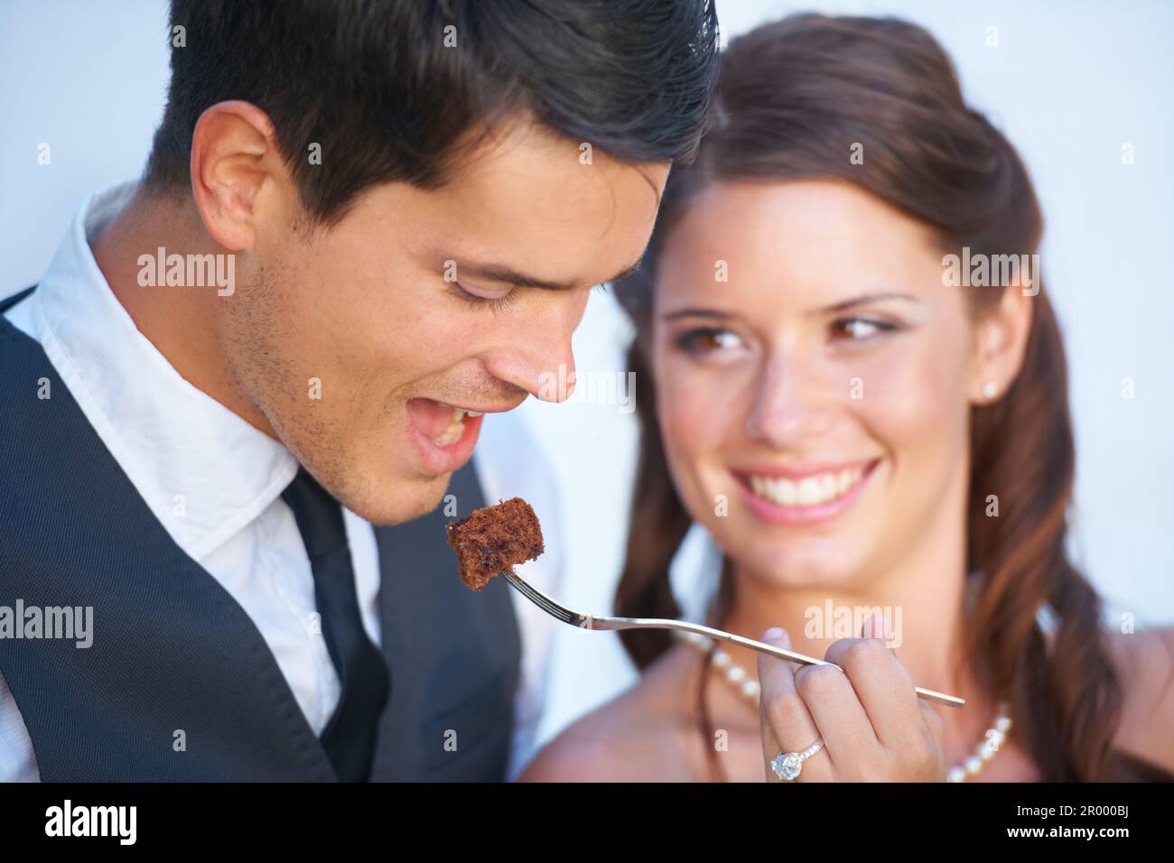 Reception fun. a young bride feeding her new husband wedding cake and ...