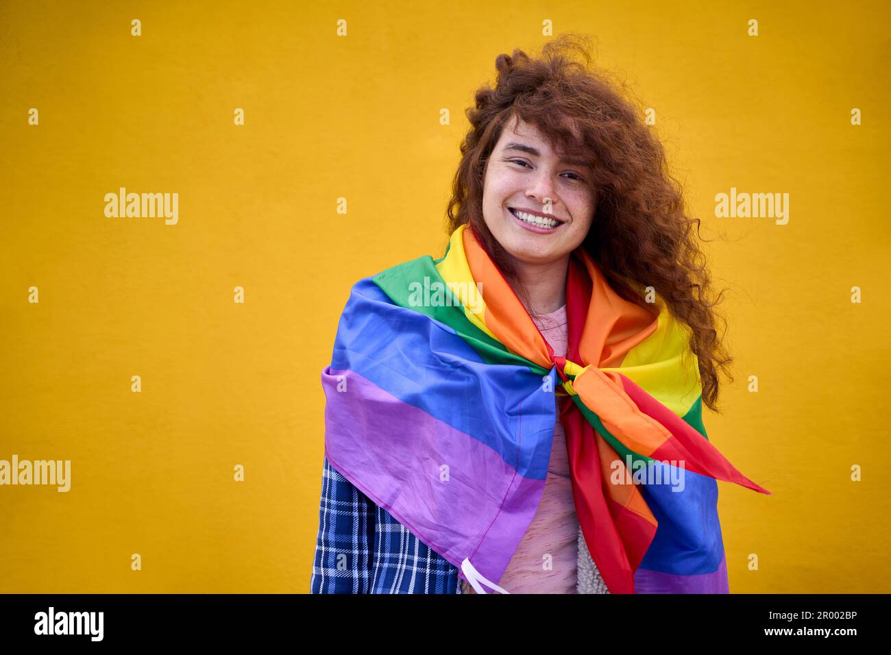 Portrait of cheerful non-binary person red hair with rainbow flag over ...