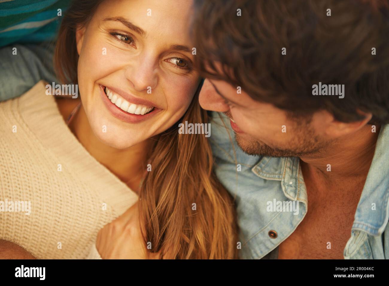 Safely wrapped in our love. A young couple smiling and cuddling under a ...