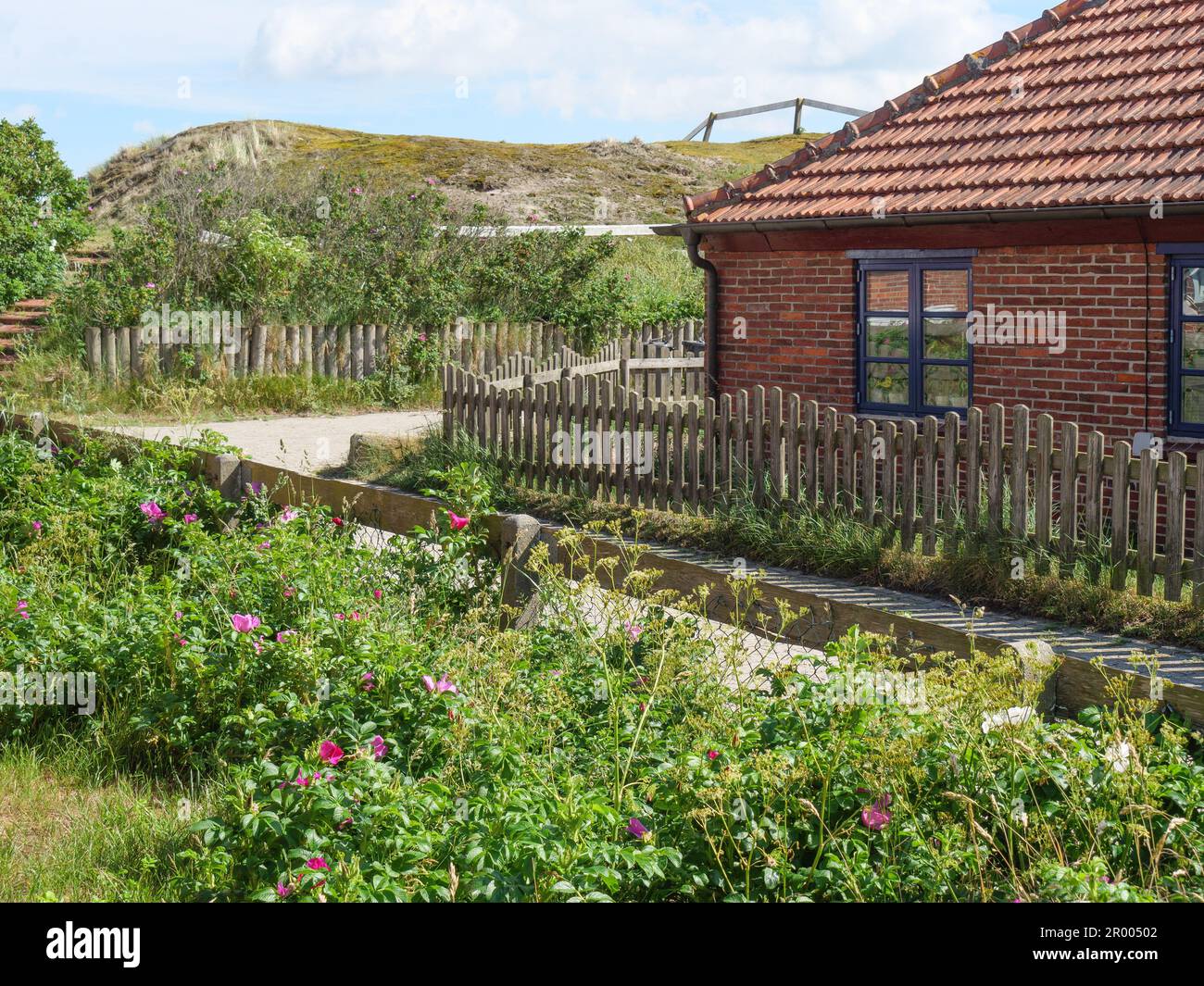 A traditional red brick house in the foreground of a lush green ...