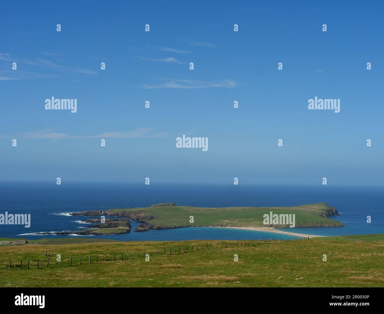 An idyllic landscape of lush green fields and vast blue ocean ...