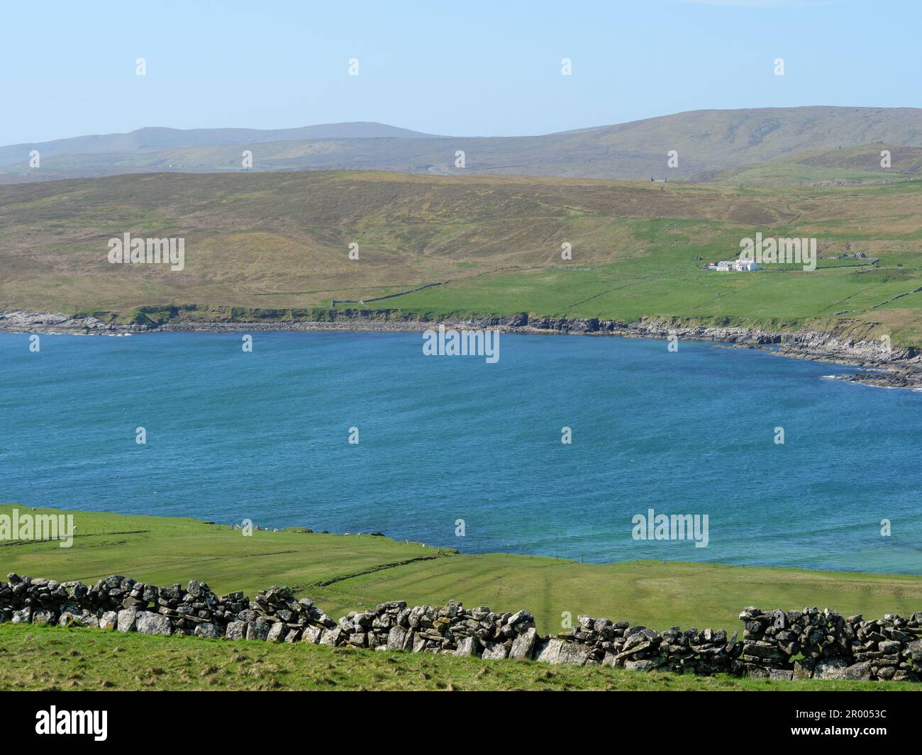 A scenic landscape of an island featuring lush green grass, large rocks ...