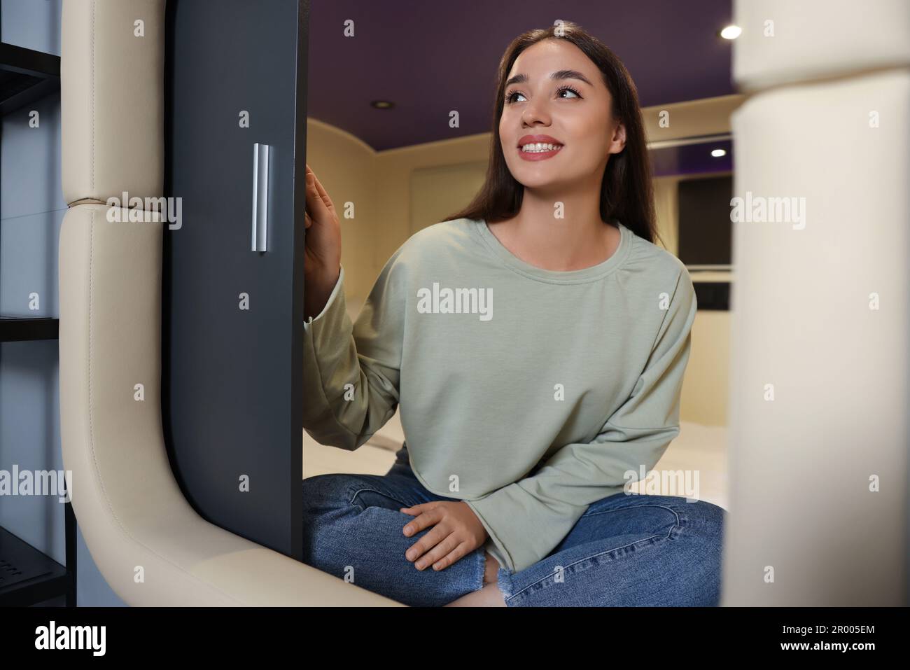 Happy young woman closing door of capsule in pod hostel Stock Photo - Alamy
