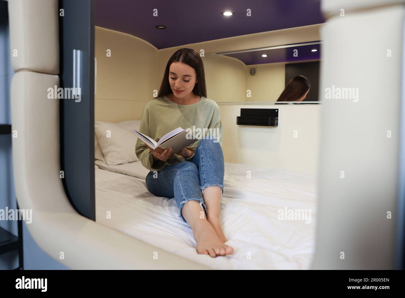 Young woman reading book in capsule of pod hostel Stock Photo - Alamy