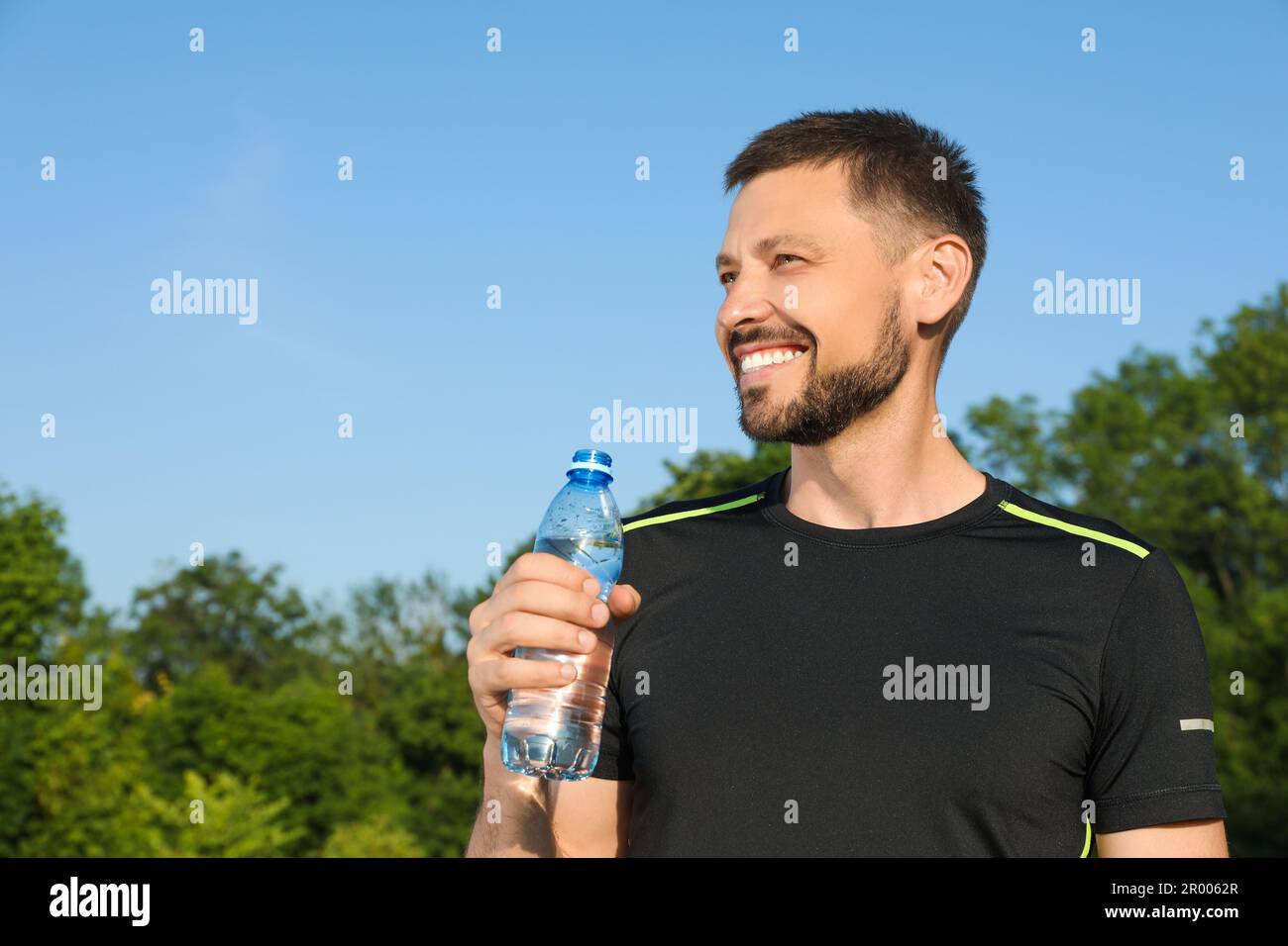 Happy man with bottle of water on hot summer day. Refreshing drink ...