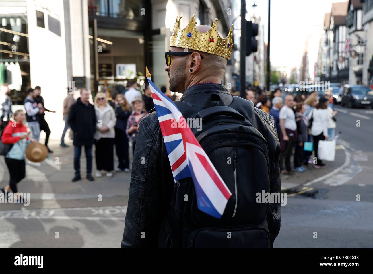 Aperson wearing a crown and flag crosses the street ahead of the Royal ...