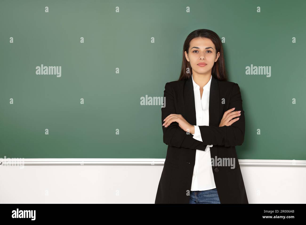 Young teacher standing at blackboard in classroom. Space for text Stock ...