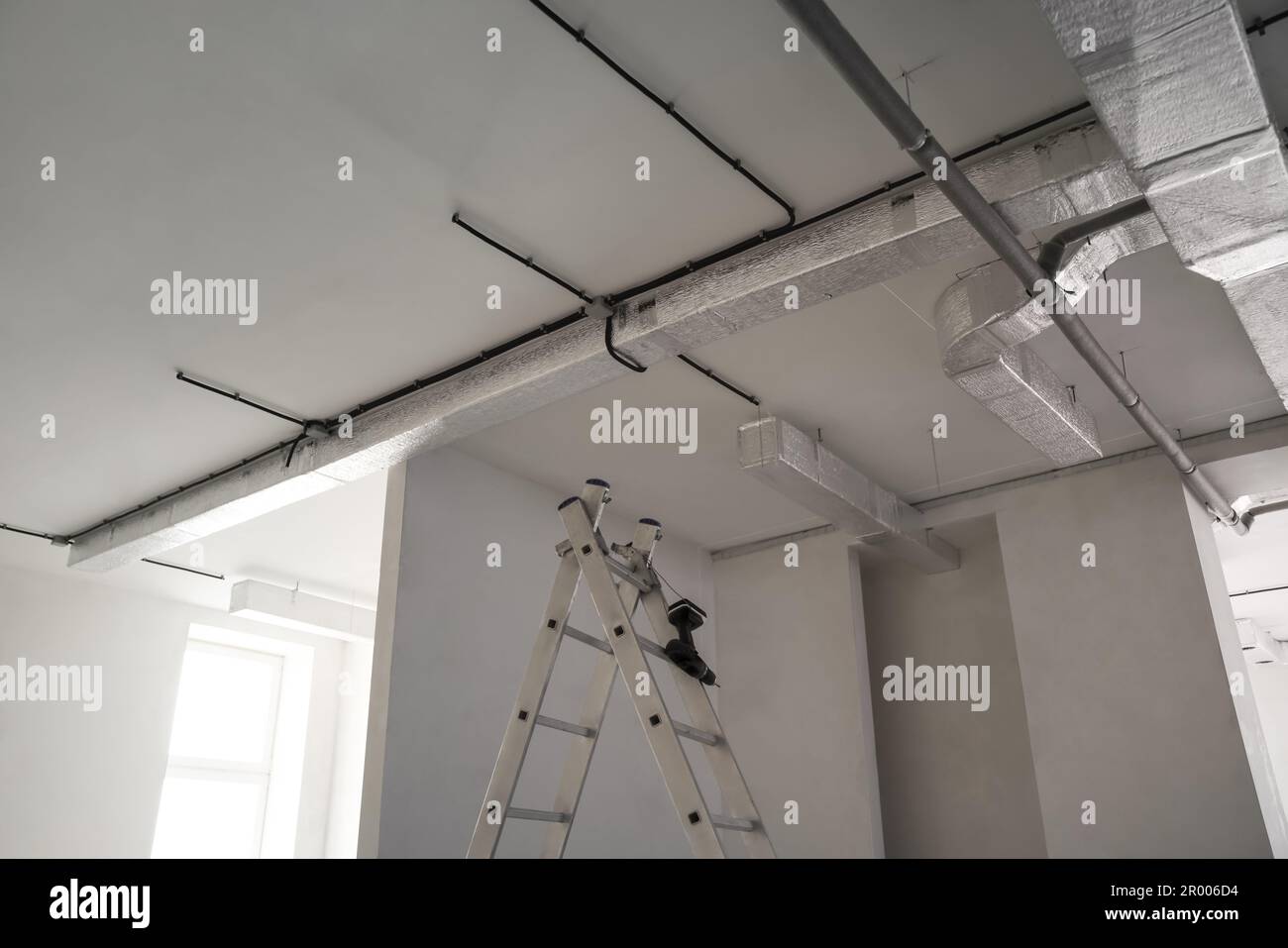 Conduits with cables and ventilation system on white ceiling, low angle ...