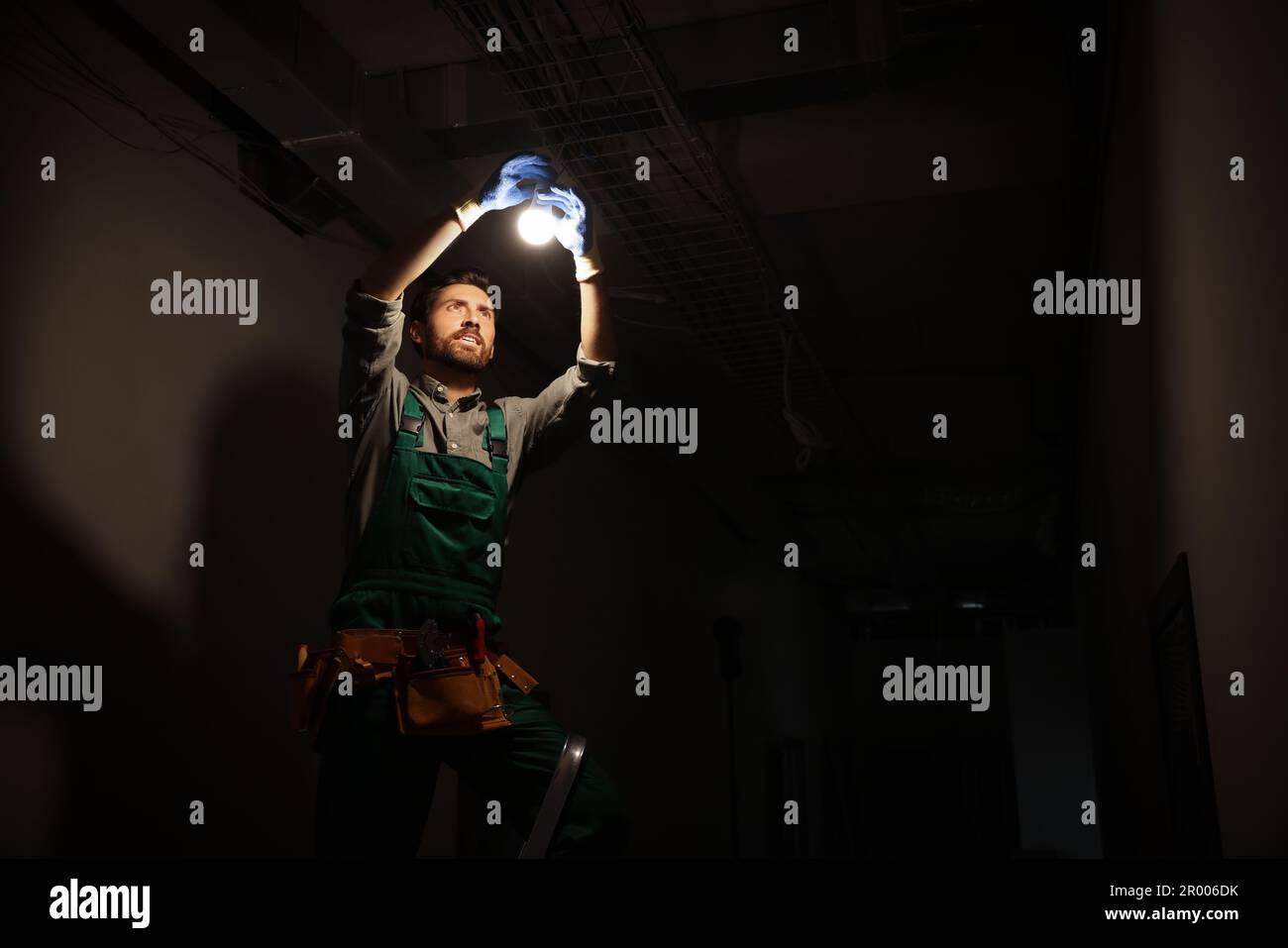 Electrician changing light bulb indoors in darkness Stock Photo - Alamy